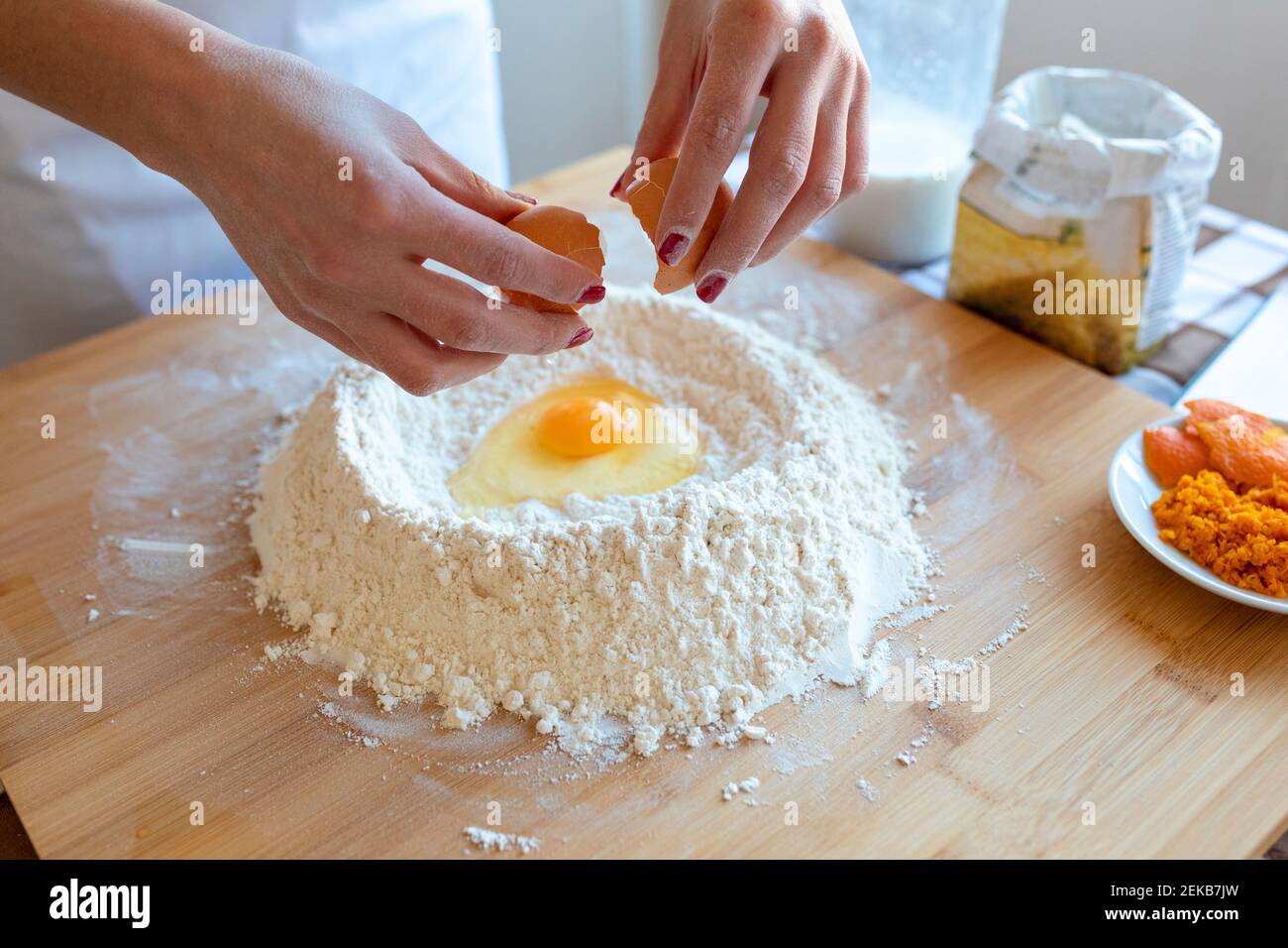 Woman breaking egg pile flour hi-res stock photography and images - Alamy
