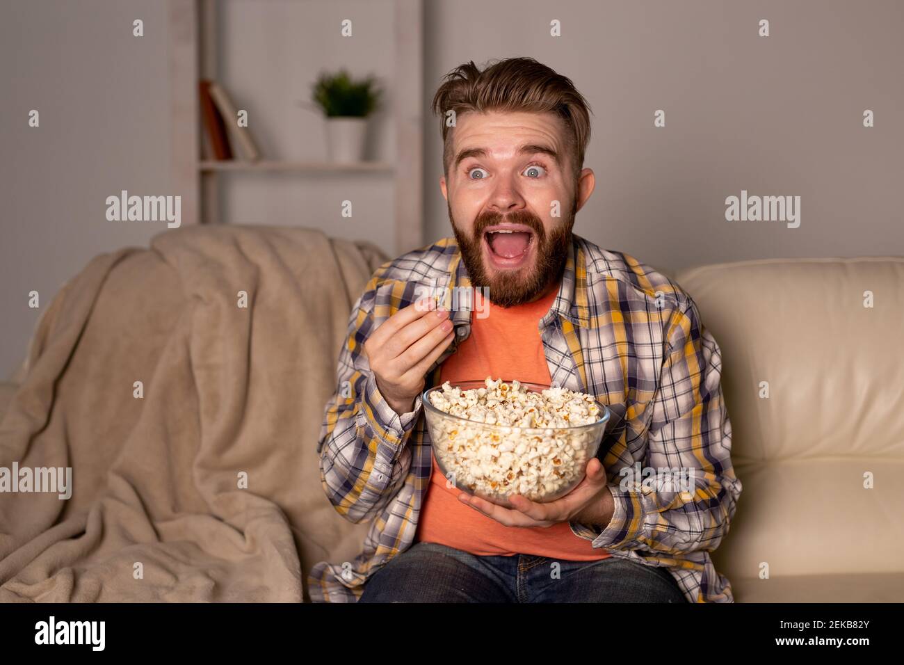 Bearded man watching film or sport games TV eating popcorn in house at ...