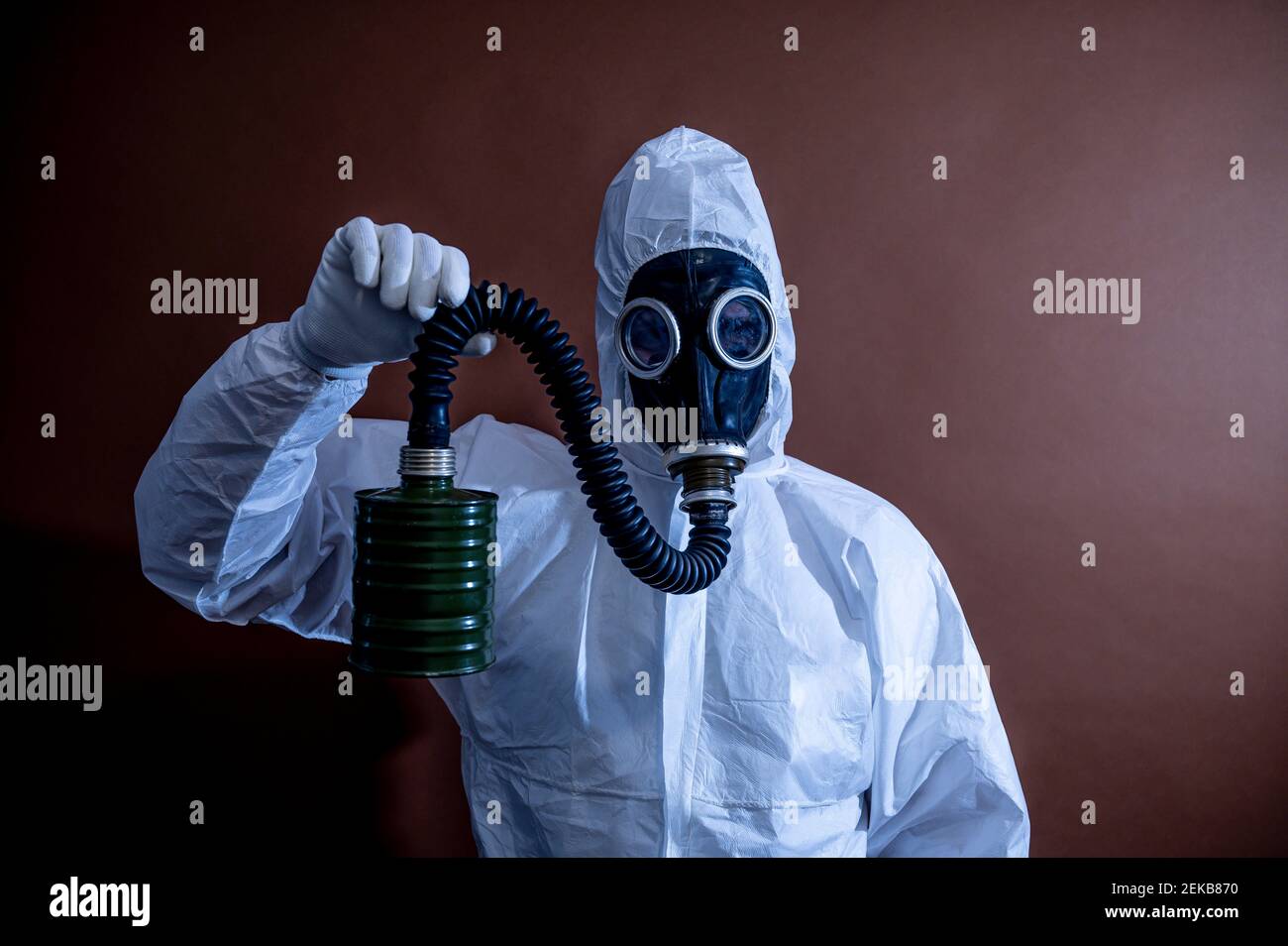 Mature in protective coveralls holding pipe of gas mask Stock Photo - Alamy