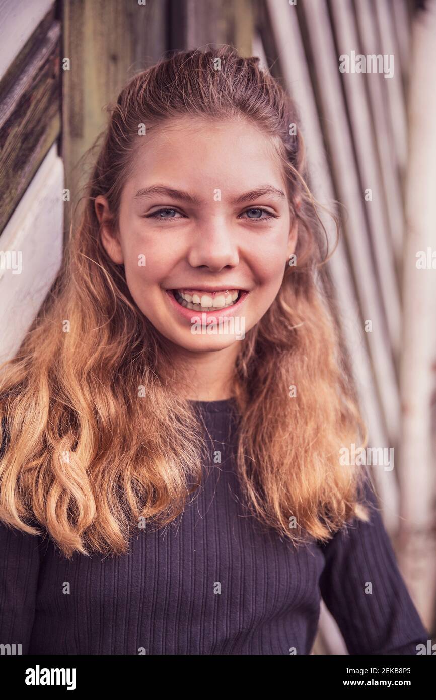 Smiling girl staring while standing against barn door Stock Photo - Alamy