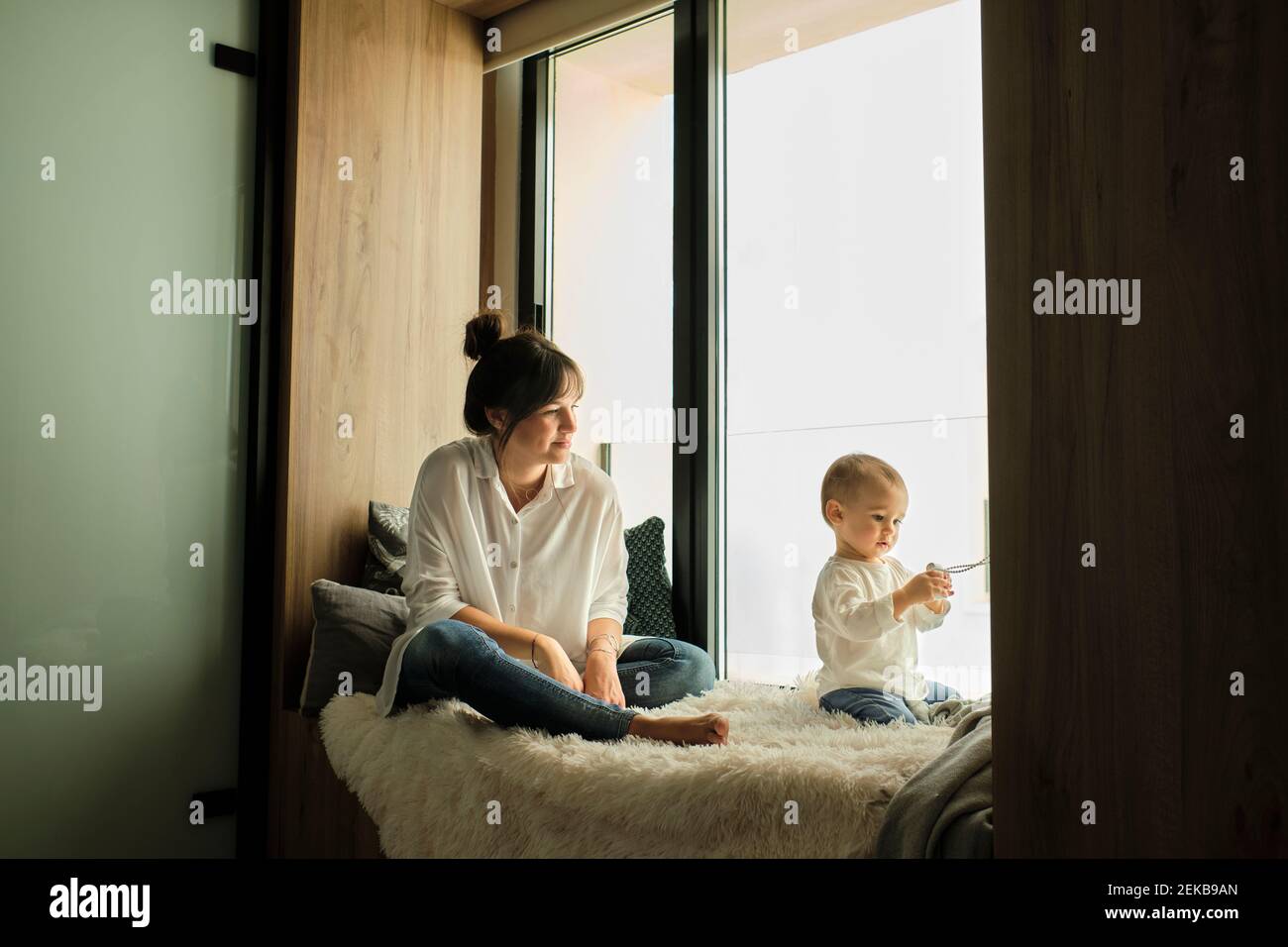 Mother sitting at the window with baby daughter Stock Photo - Alamy