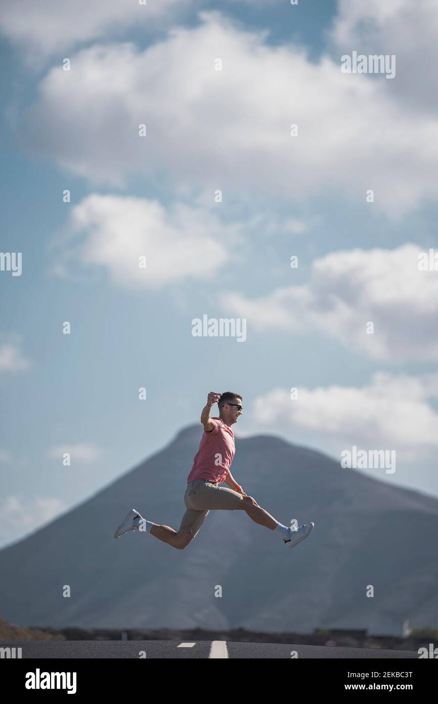Happy male tourist jumping over highway road lanzarote hi-res stock ...