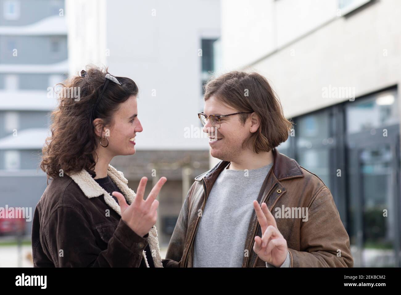 Smiling couple showing peace sign to each other Stock Photo - Alamy