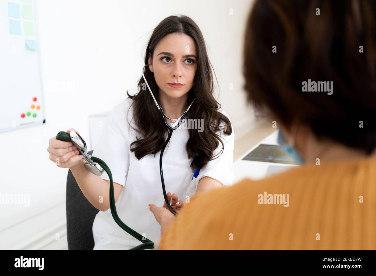 Beautiful female doctor checking blood pressure of patient in clinic ...