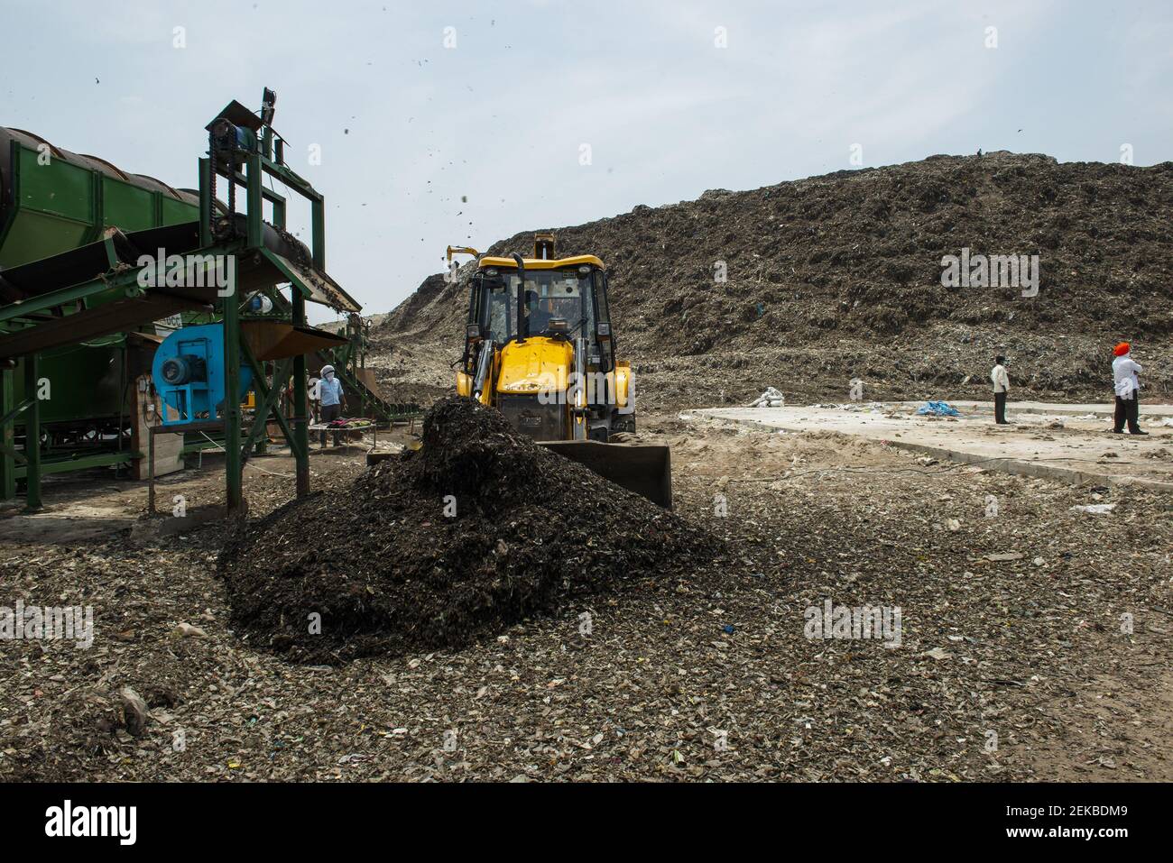 A JCB machine cleaning waste on land fill site. Waste segregation plant ...