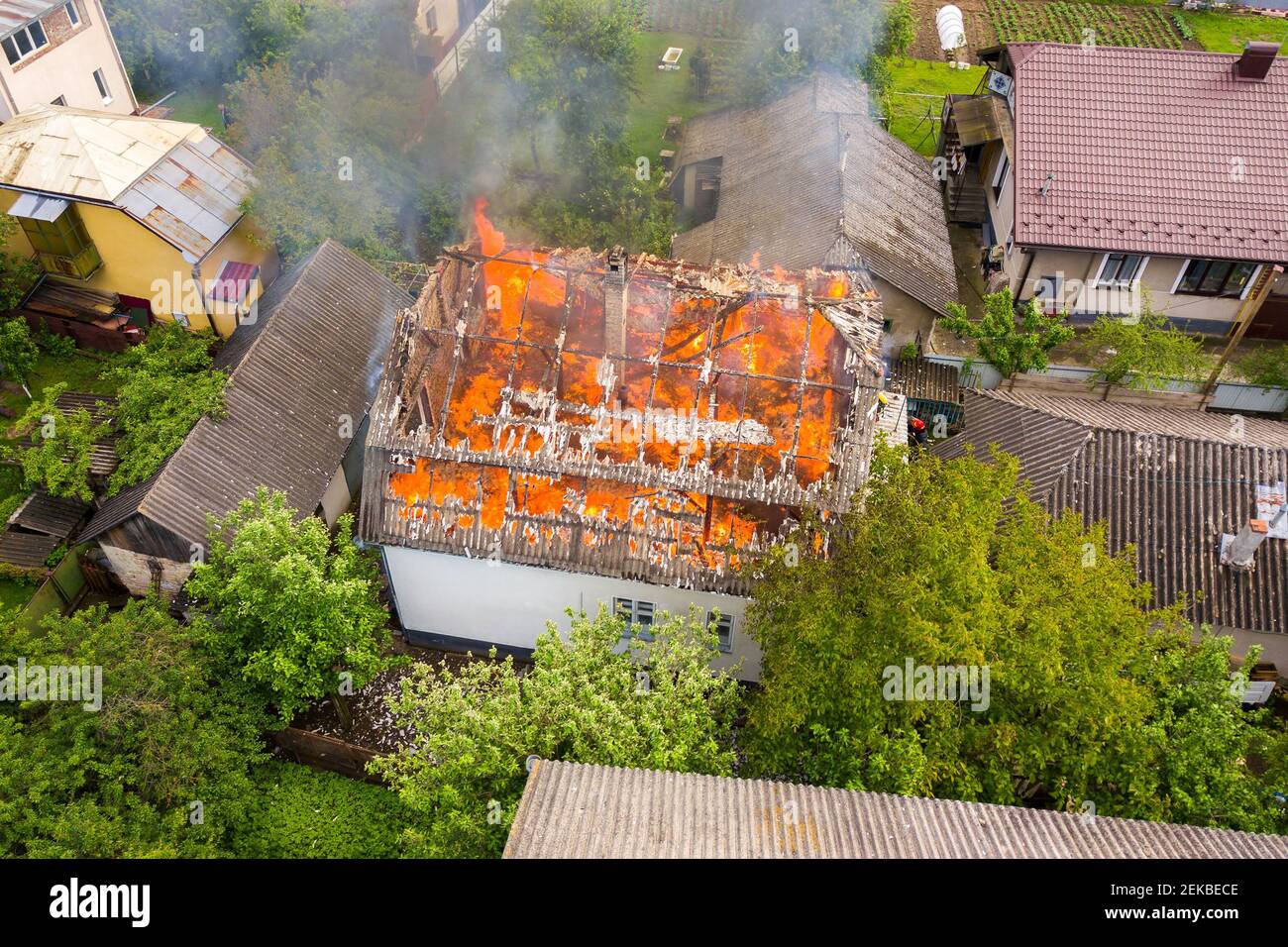 Aerial view of a house on fire with orange flames and white thick smoke ...