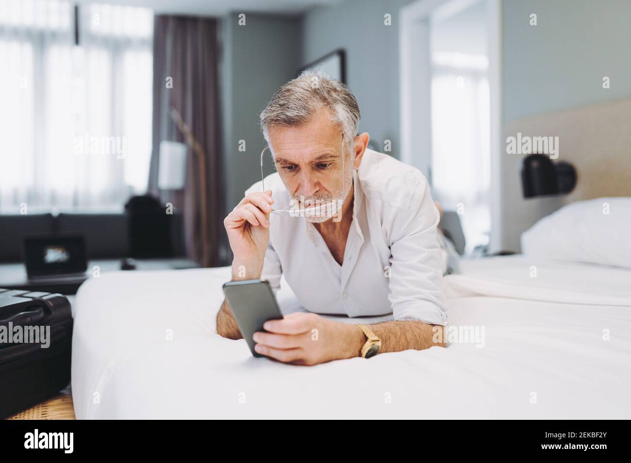 Man using smart phone while lying on bed in hotel room Stock Photo - Alamy