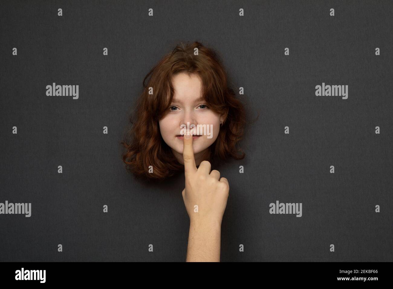 Studio shot of head of teenage girl shushed by male hand Stock Photo ...