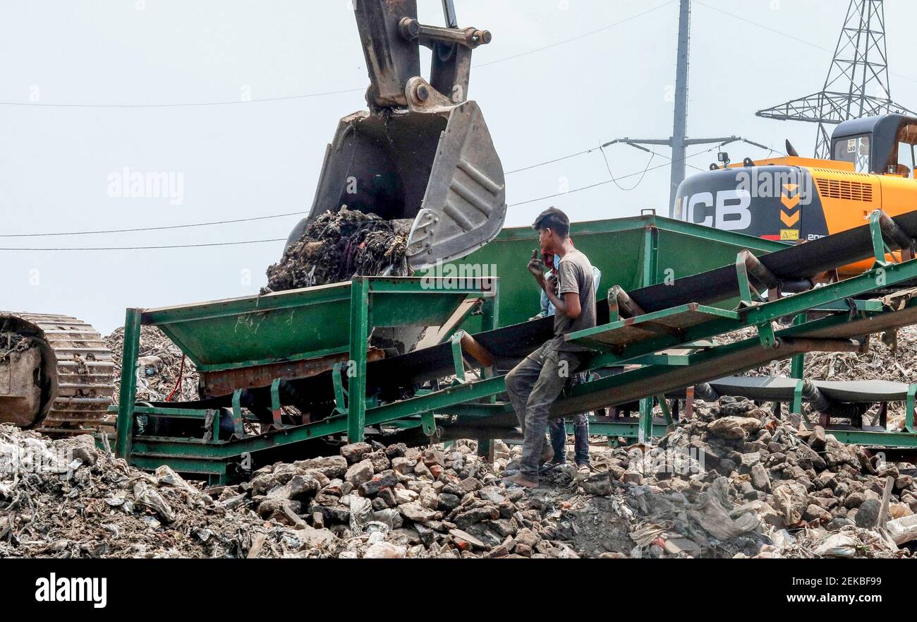 A worker smokes as he watches the Trommel machine separate solid waste ...