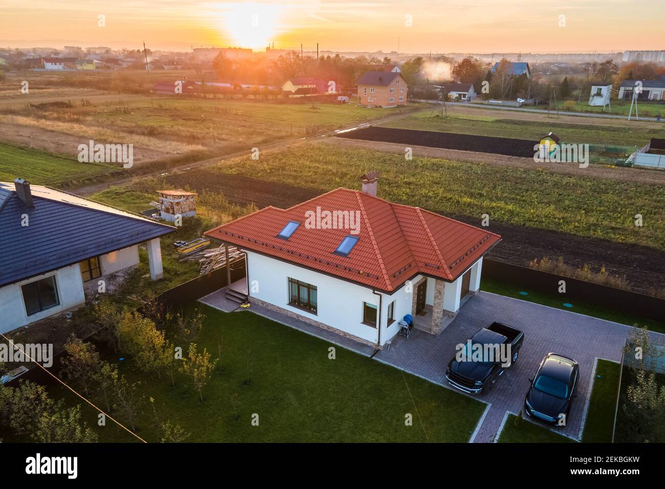 Aerial view of a private suburban house with parked cars in back yard ...