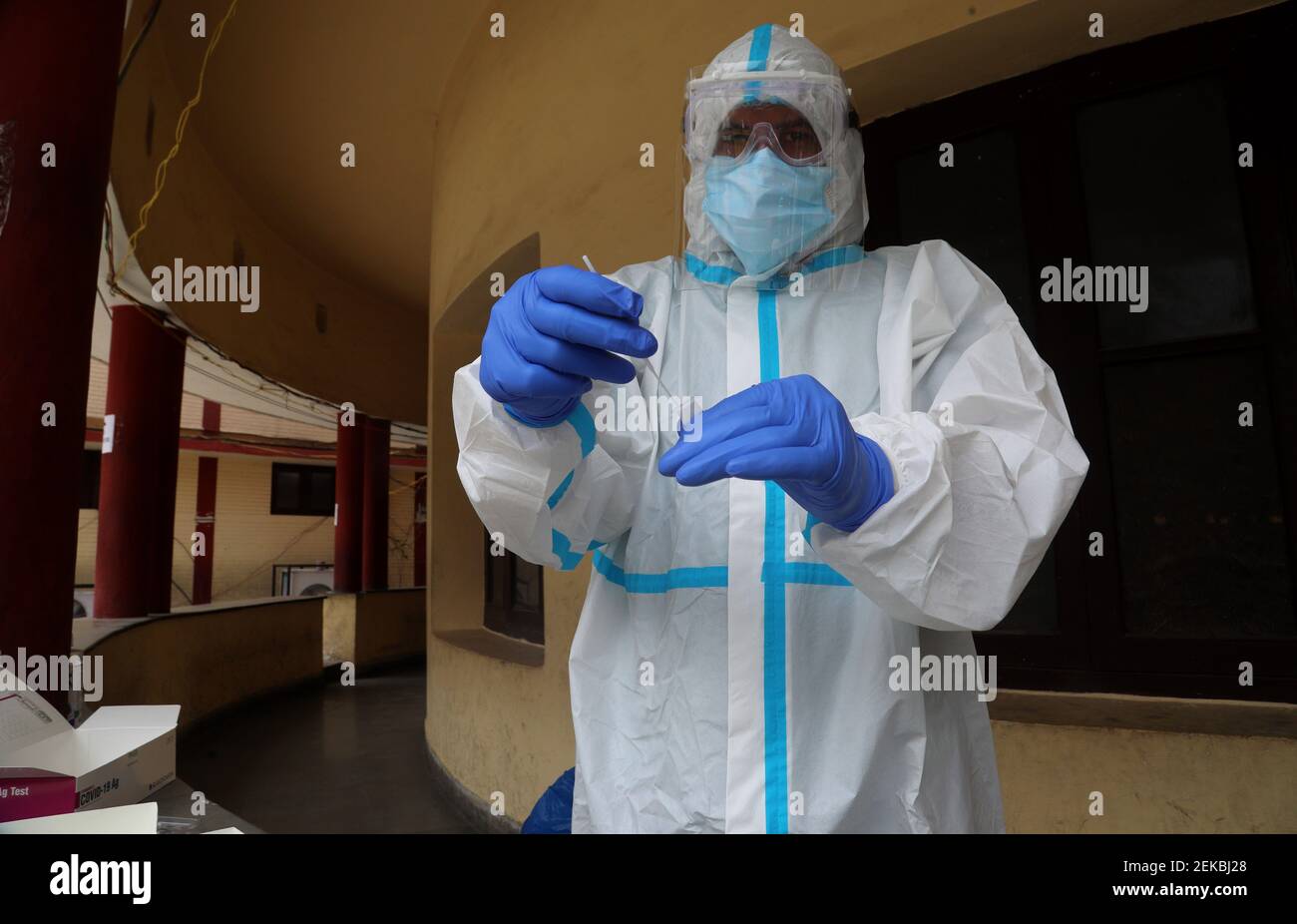 A health worker wearing personal protective equipment (PPE) holding a ...