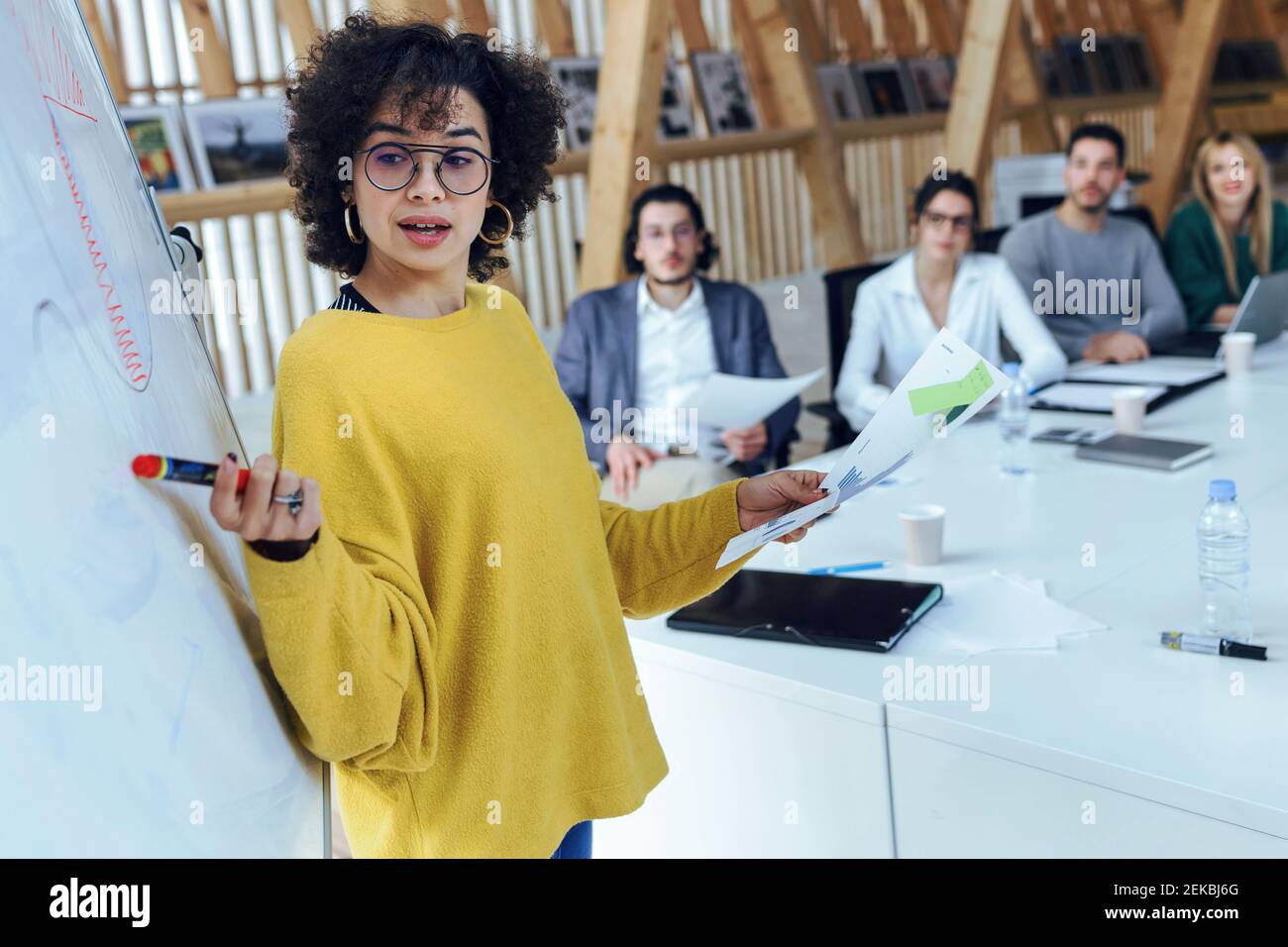 Young female hipster professional pointing at whiteboard while ...