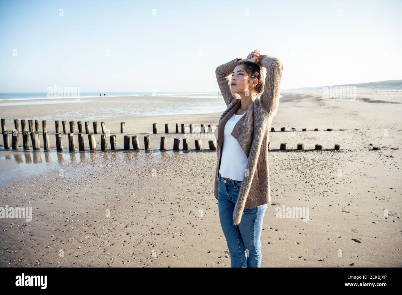 Beautiful woman contemplating while standing on sand at beach Stock ...