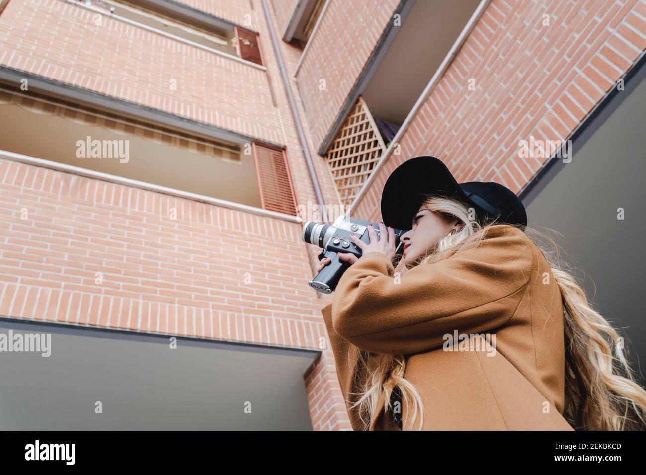Blond woman filming building through vintage video camera Stock Photo ...