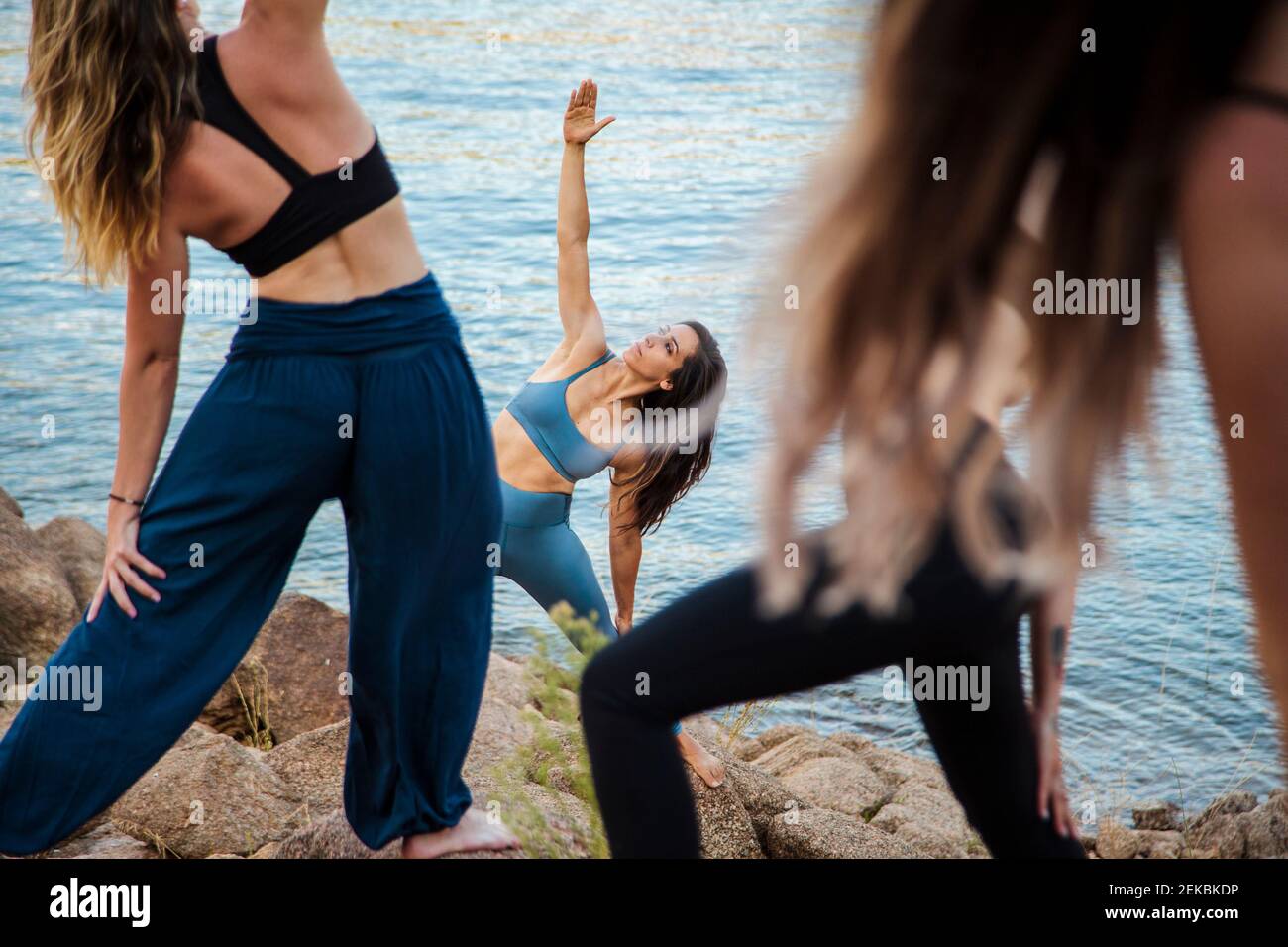 Young female yoga instructor teaching stretching exercise to women ...
