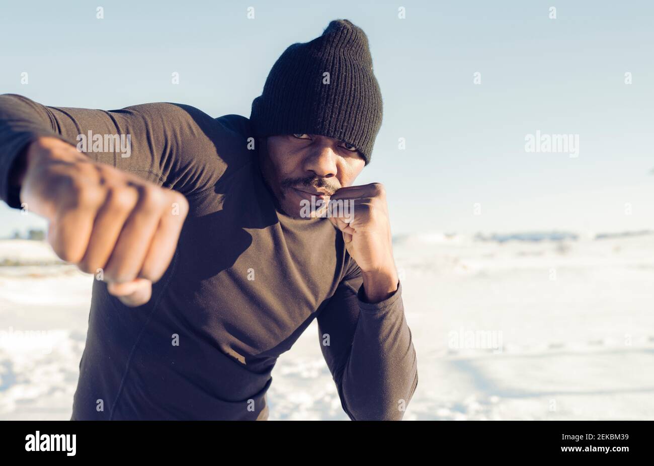 Male athlete wearing knit hat showing fist while practicing boxing ...
