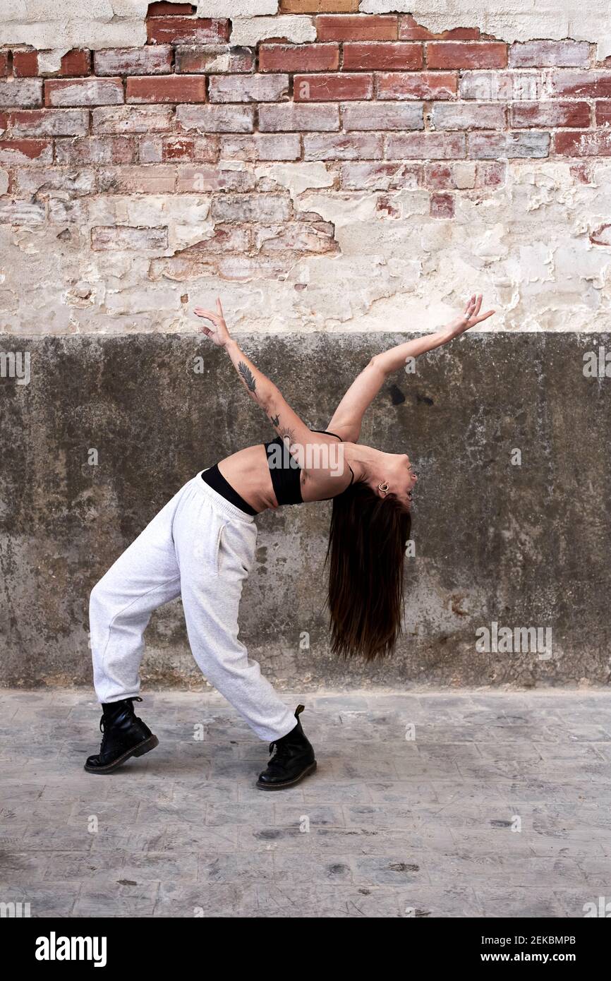 Flexible female dancer bending backwards while dancing against old ...