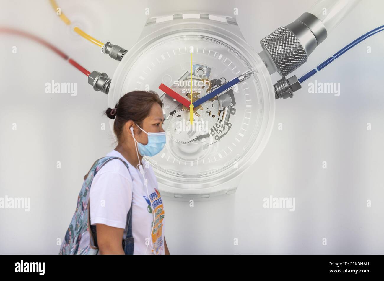 A pedestrian wearing a face mask walks past the Swiss multinational ...