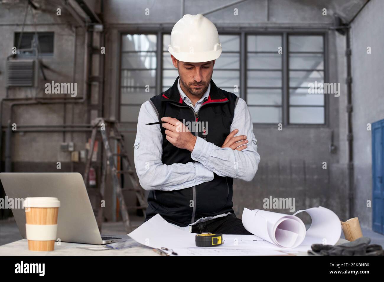 Male engineer thinking while analyzing blueprint on table in building ...