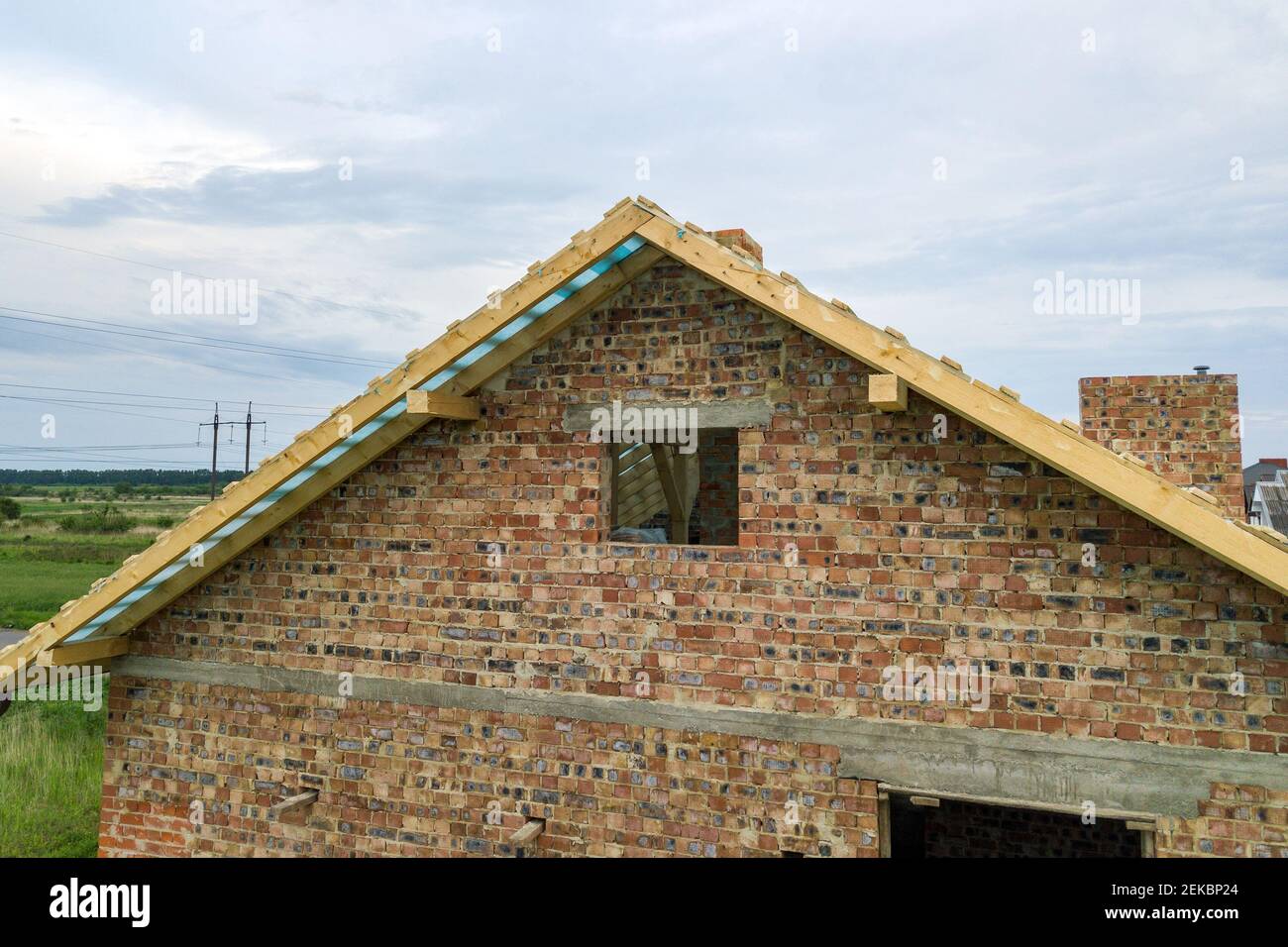 Aerial view of a brick house with wooden roof frame under construction ...