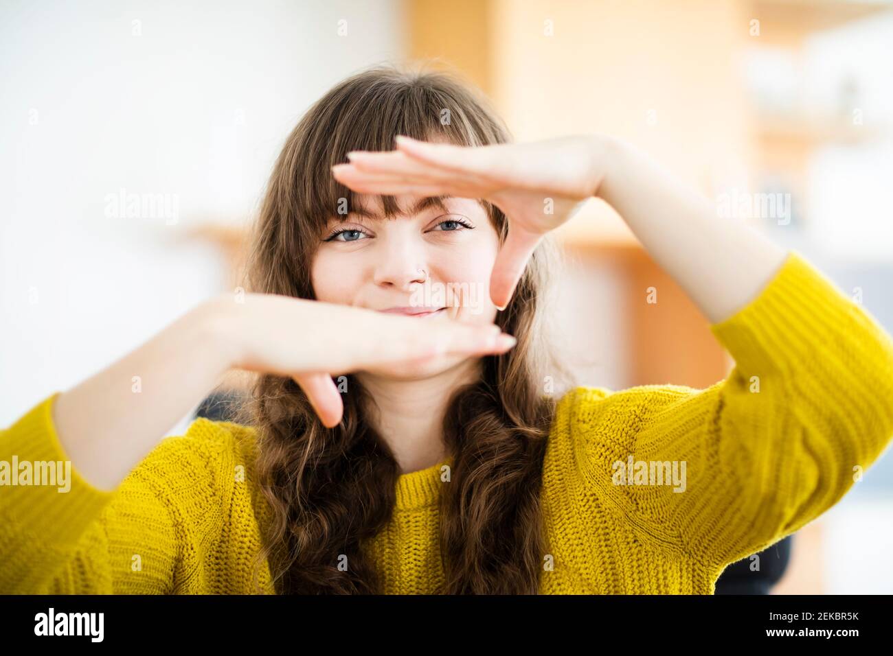 Young woman making finger frame at home Stock Photo - Alamy