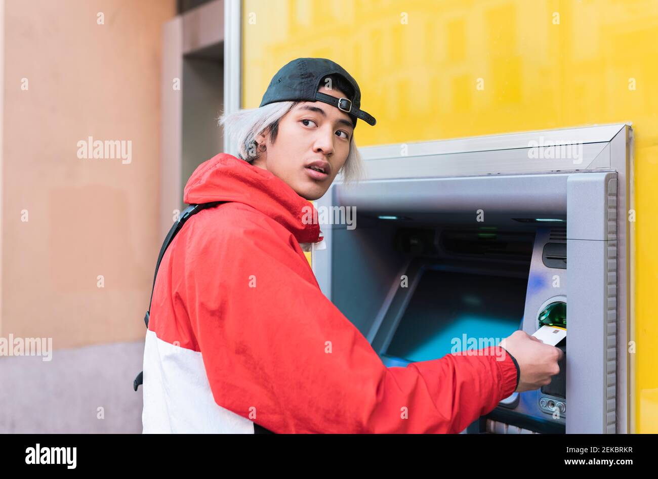 Young man withdrawing money at ATM machine Stock Photo - Alamy