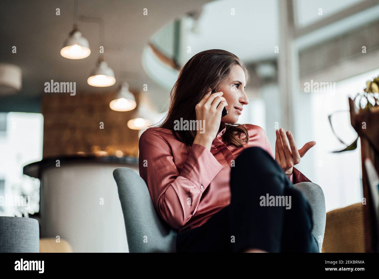 Female professional gesturing while talking on phone call in cafe Stock ...