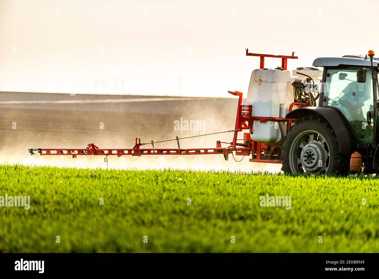 Young farmer in tractor spraying insecticide in green farm Stock Photo ...