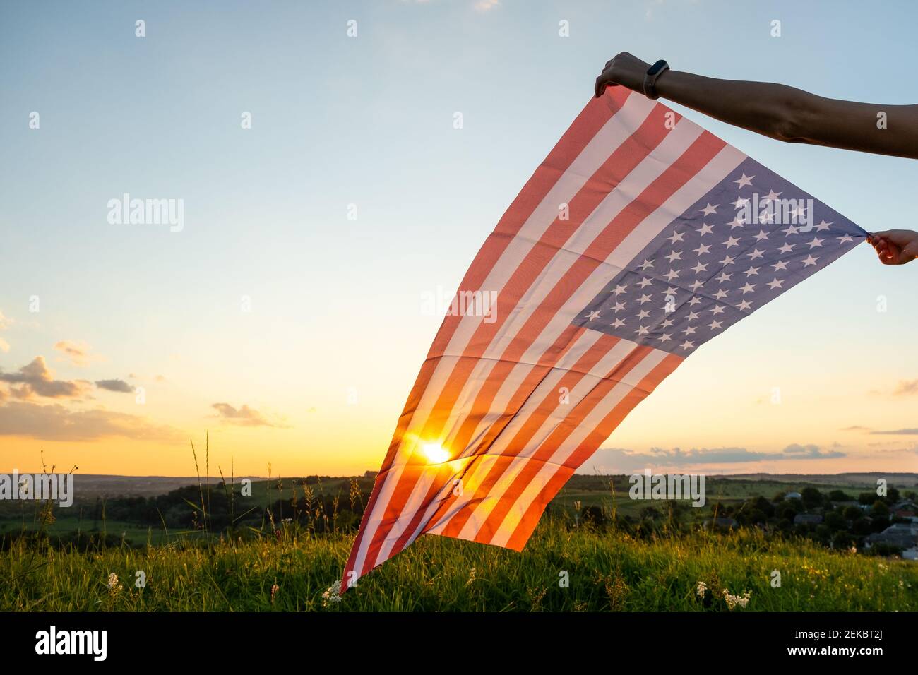 Human hands holding waving USA national flag in field at sunset Stock ...
