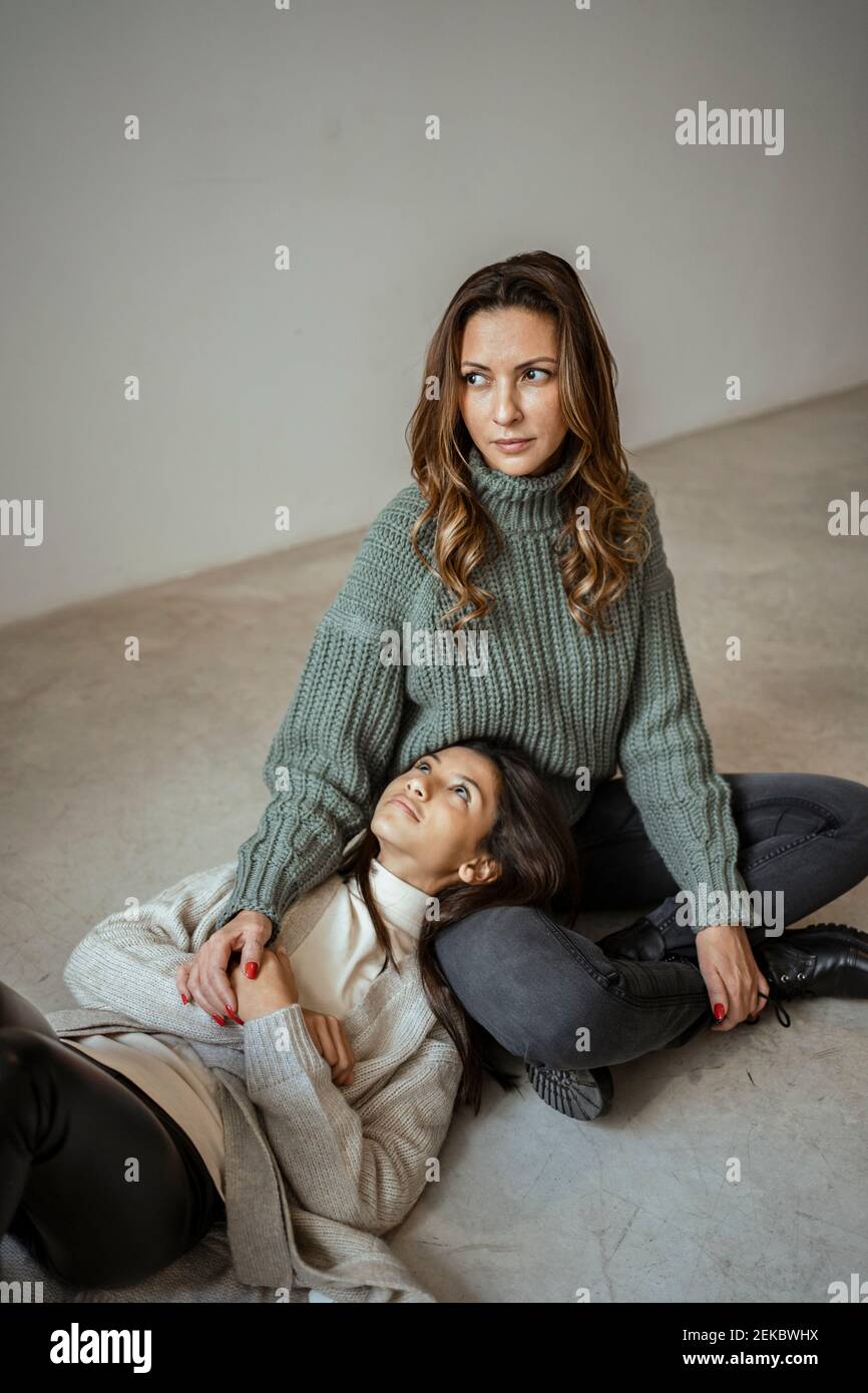 Daughter lying on mother's lap while her contemplating at home Stock ...