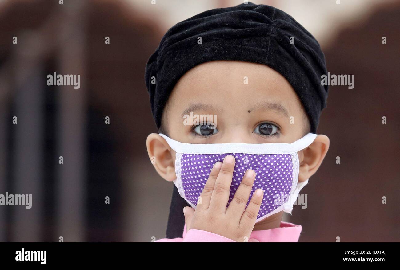 A child wearing a face mask as a preventive measure poses for a photo ...