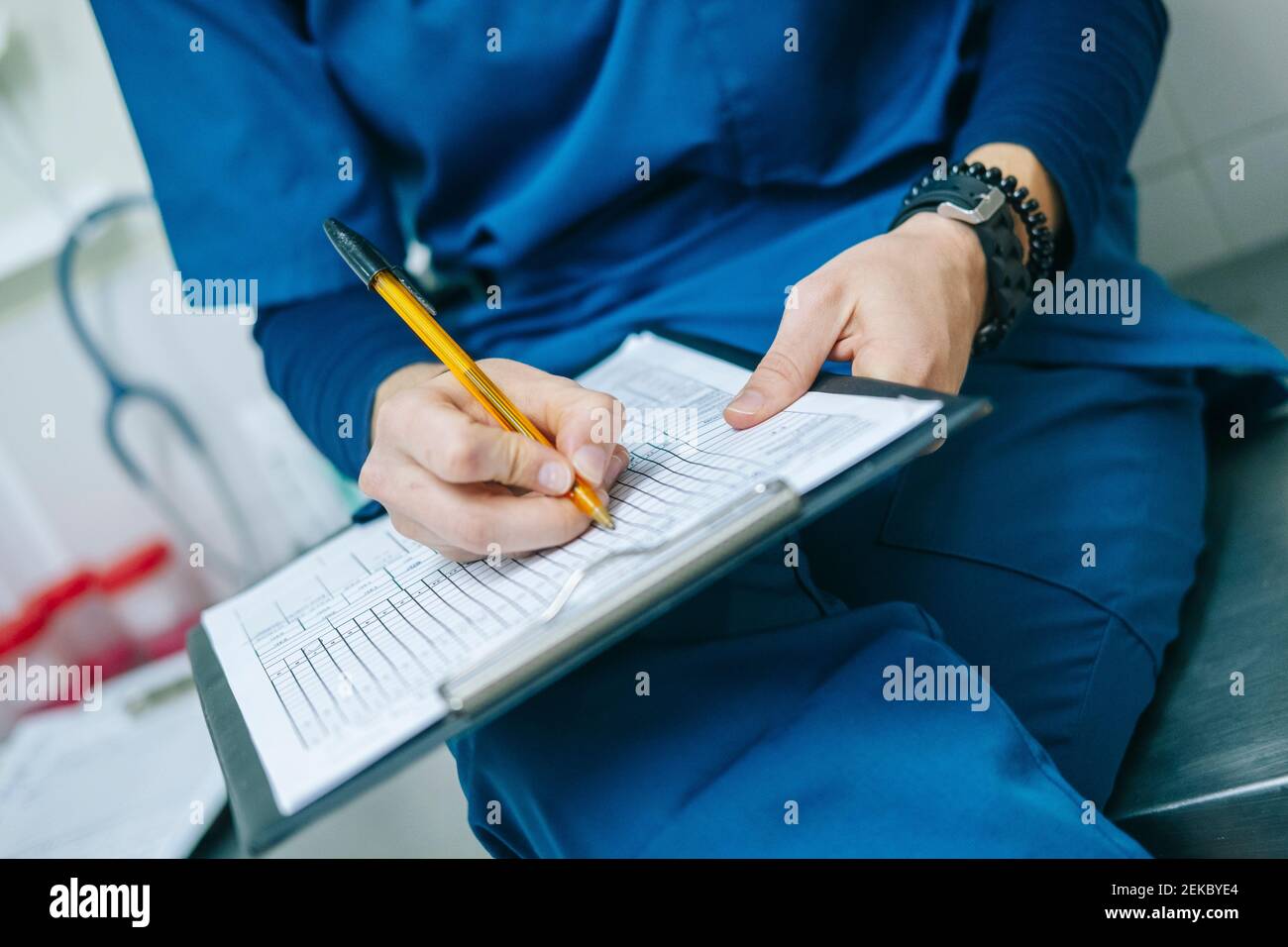 Female nurse writing medical report while sitting in hospital Stock ...
