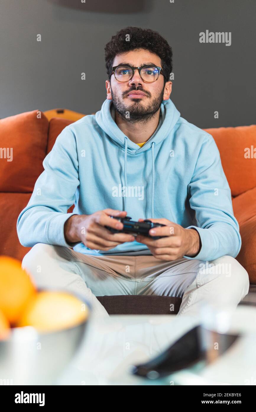 Concentrated young man playing video game in living room Stock Photo ...
