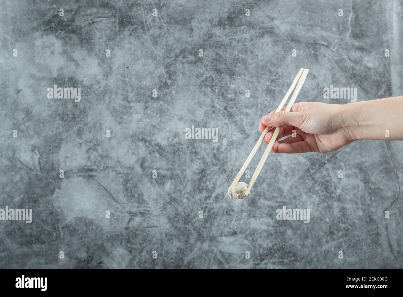 Hand holding a chopstick with a dumpling Stock Photo - Alamy