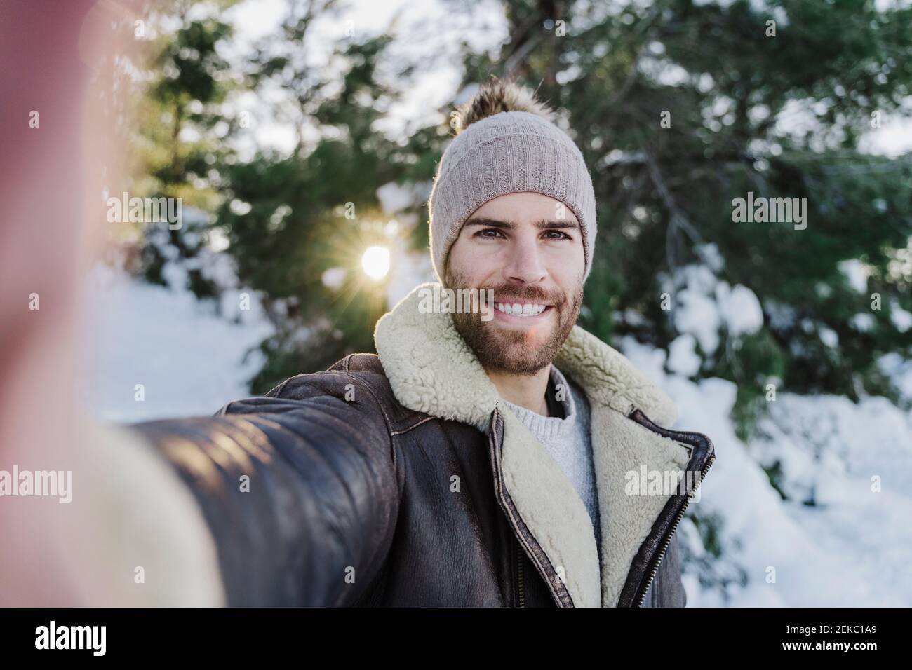 Happy young man taking selfie against trees in cold weather Stock Photo ...