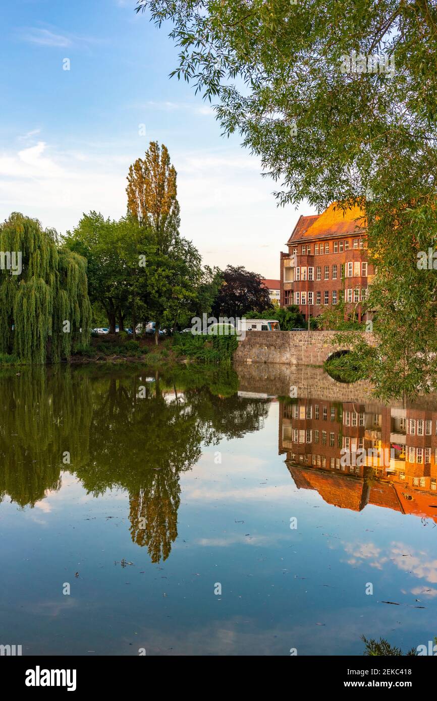 Germany, Berlin, Trees reflecting on surface of shiny Weissensee lake ...