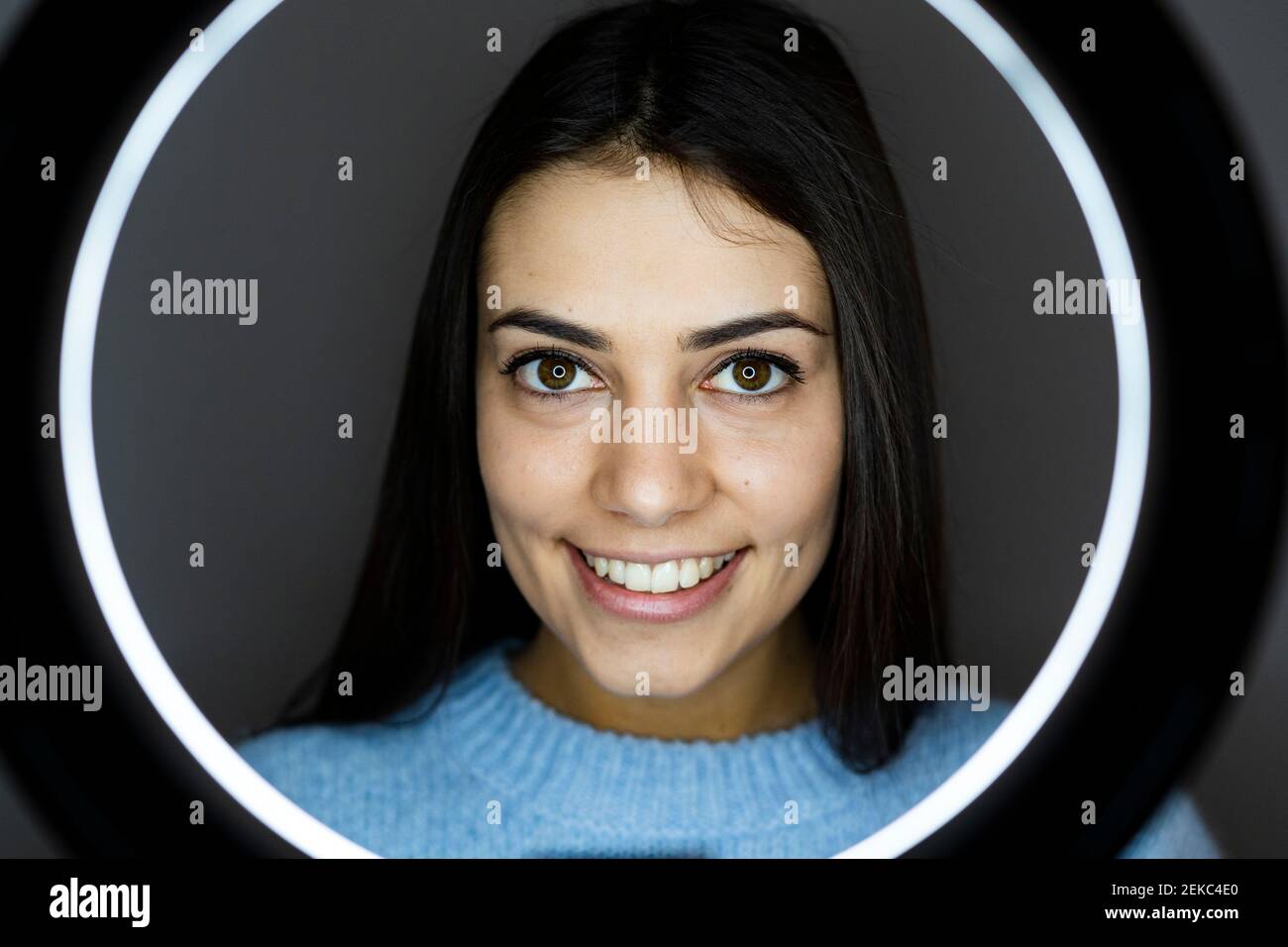 Young woman with illuminated circular camera flash smiling while ...