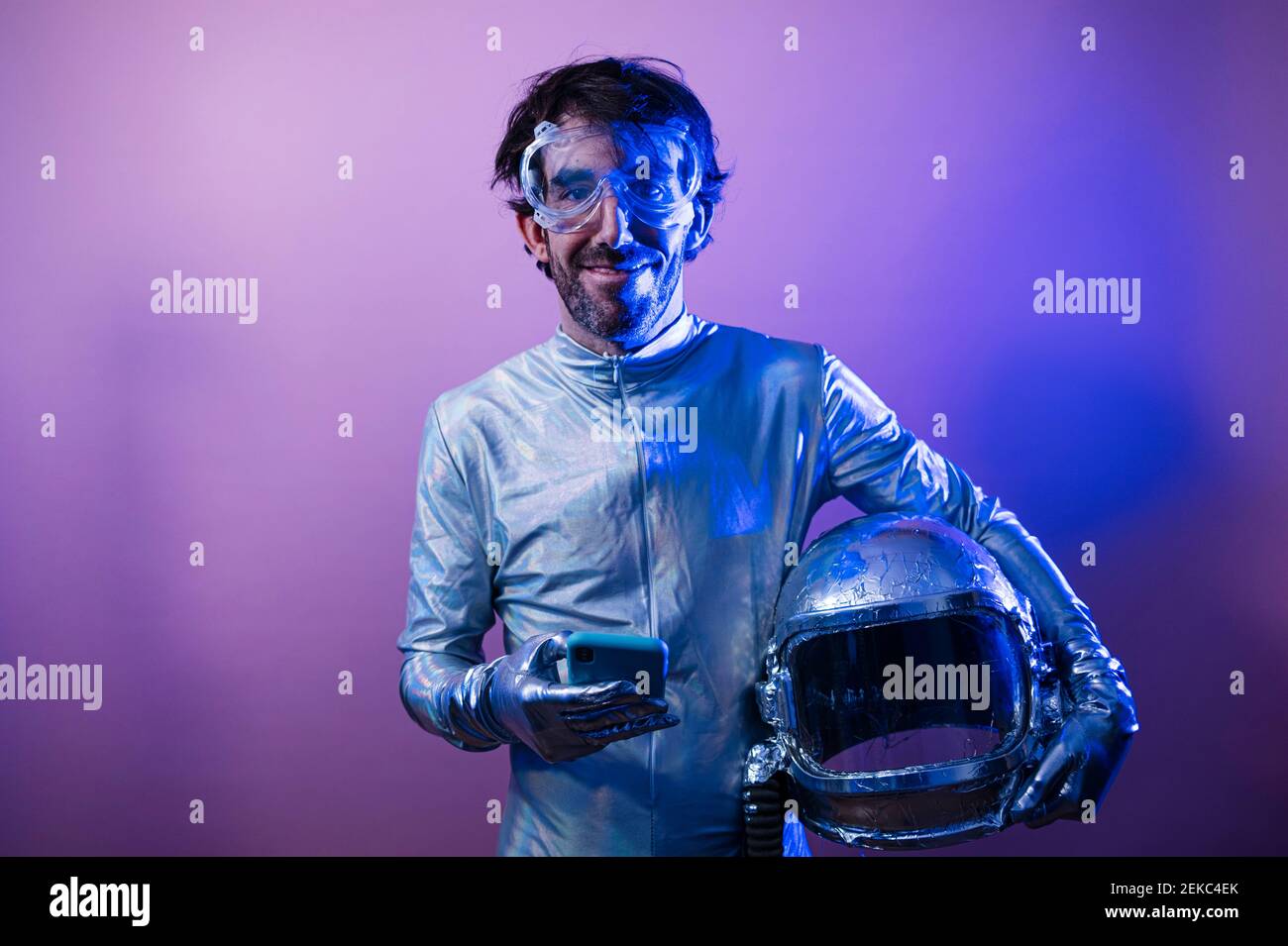 Male astronaut with hand on hip holding space helmet while standing ...