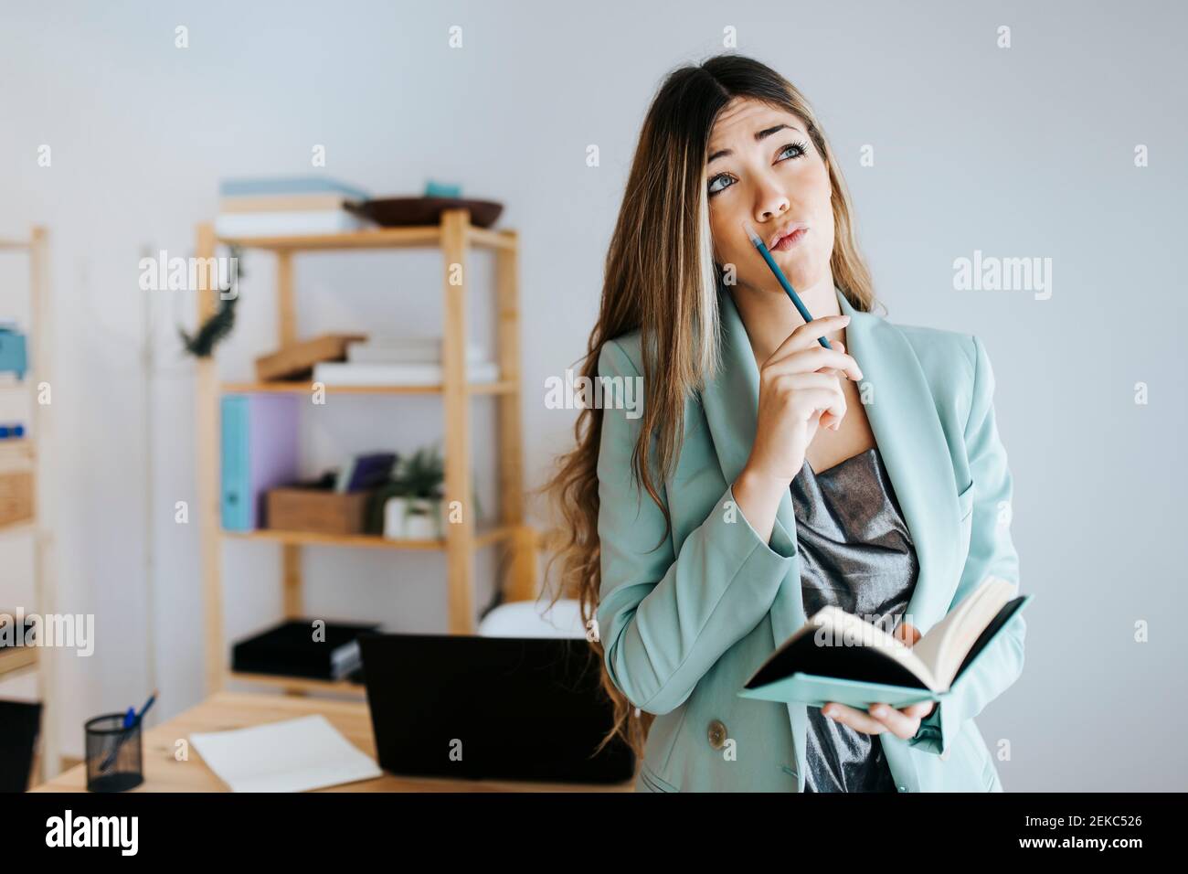 Businesswoman thinking while writing in diary at office Stock Photo - Alamy