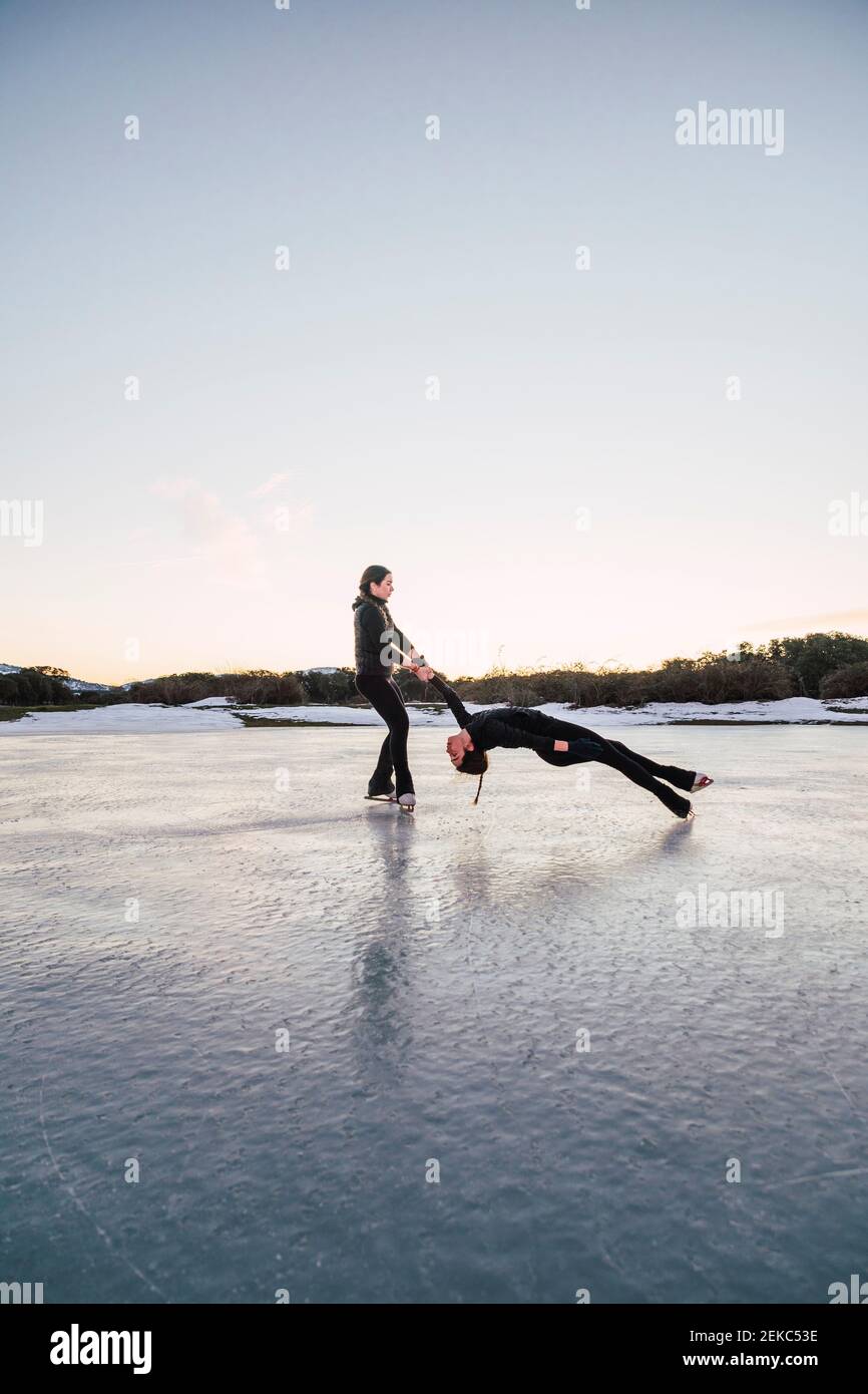 Two female figure skaters performing death spiral on frozen lake Stock ...