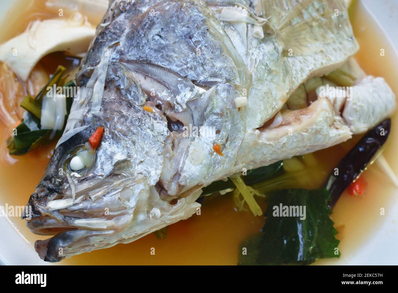 spicy bass fish head and slice coconut shoot in Tom Yum soup on plate ...