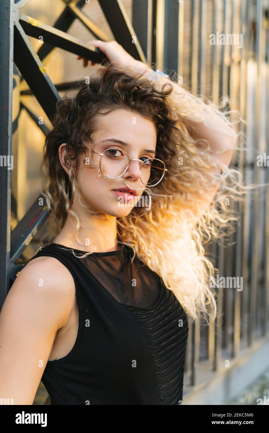 Confident young woman leaning on gate Stock Photo - Alamy