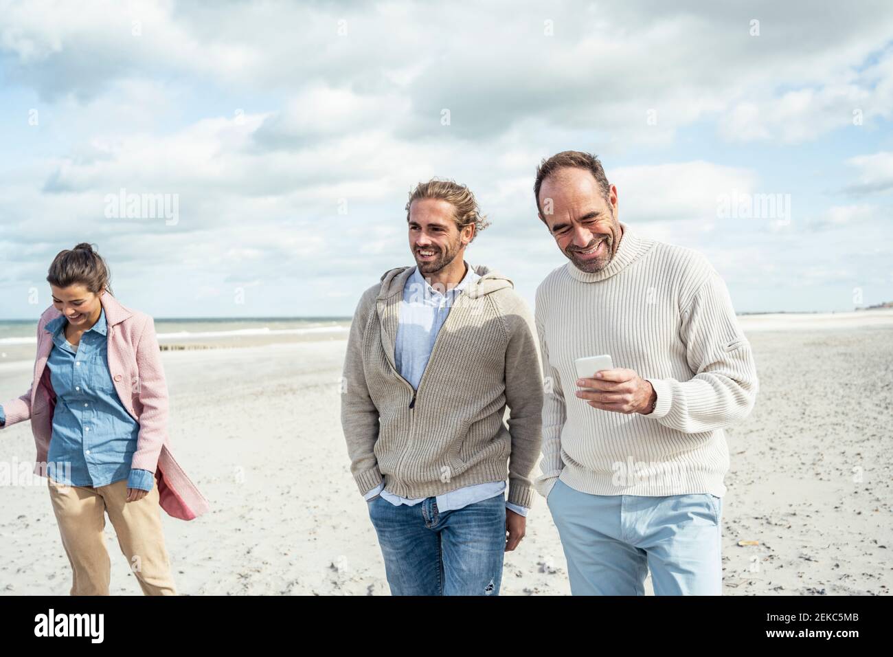 Two men walking and talking side by side along sandy beach Stock Photo ...