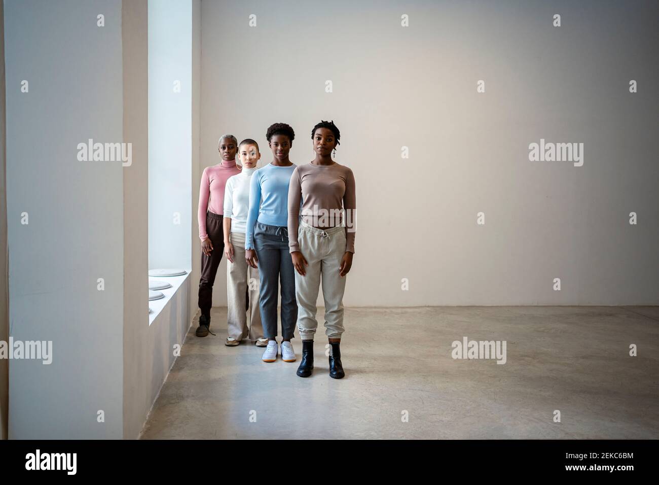 Female friends standing in row against wall at home Stock Photo - Alamy