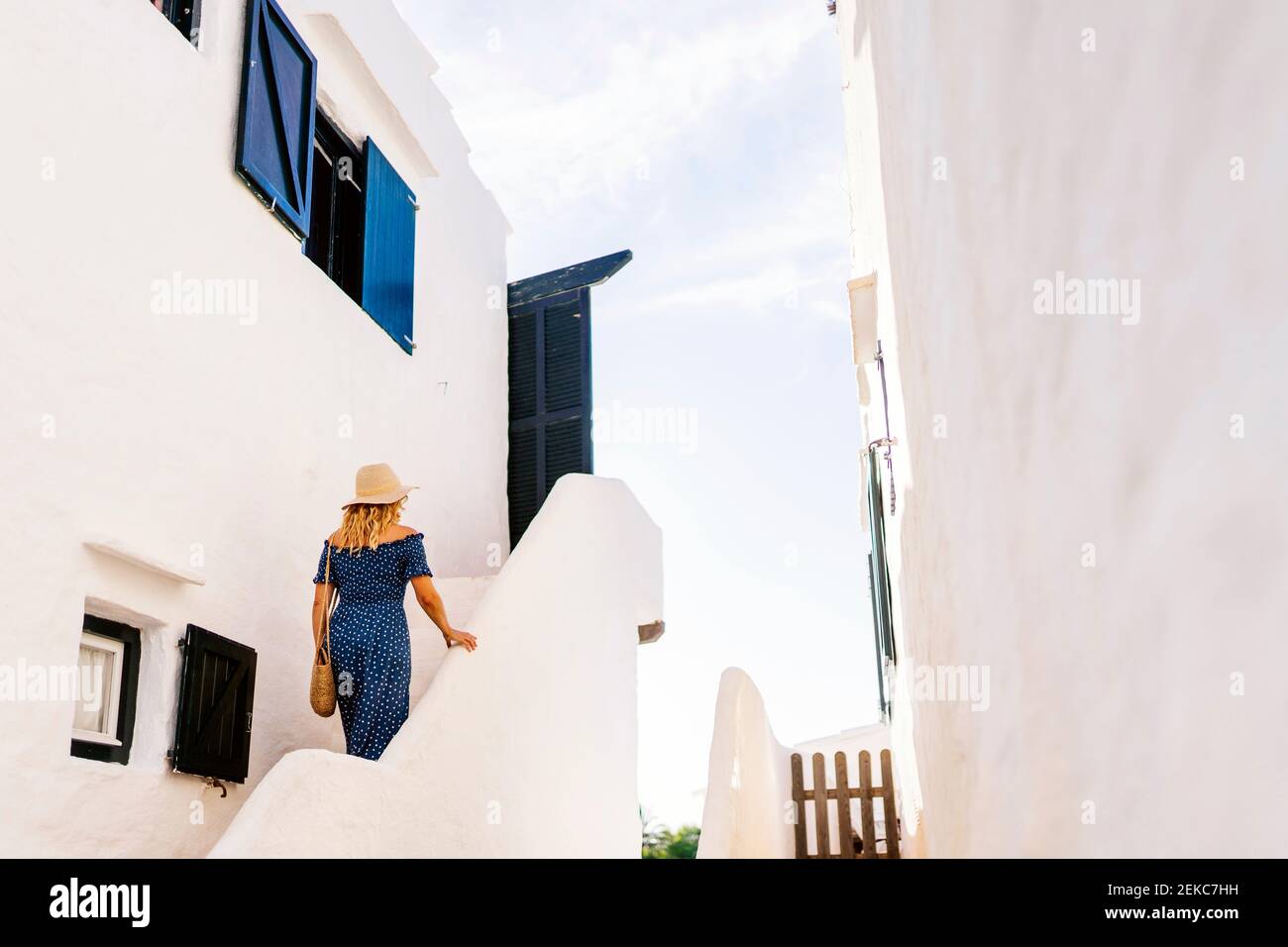 Mature woman climbing on steps of whitewashed building in Binibeca ...