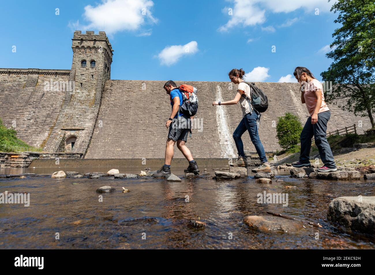 Male and female hikers walking on stone over water during vacations ...