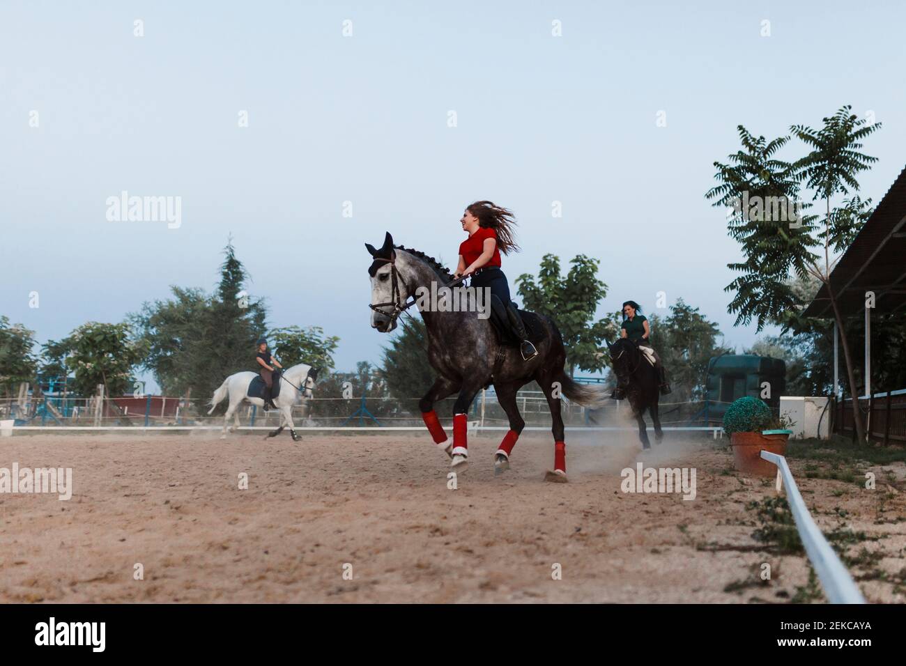 Female friends horseback riding together in farm during weekend Stock ...