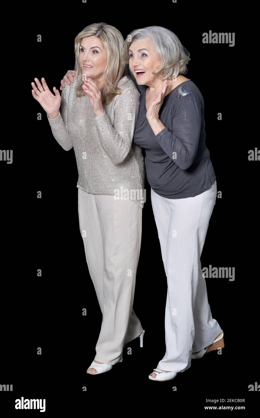 Close up portrait of Two beautiful senior women posing against black ...