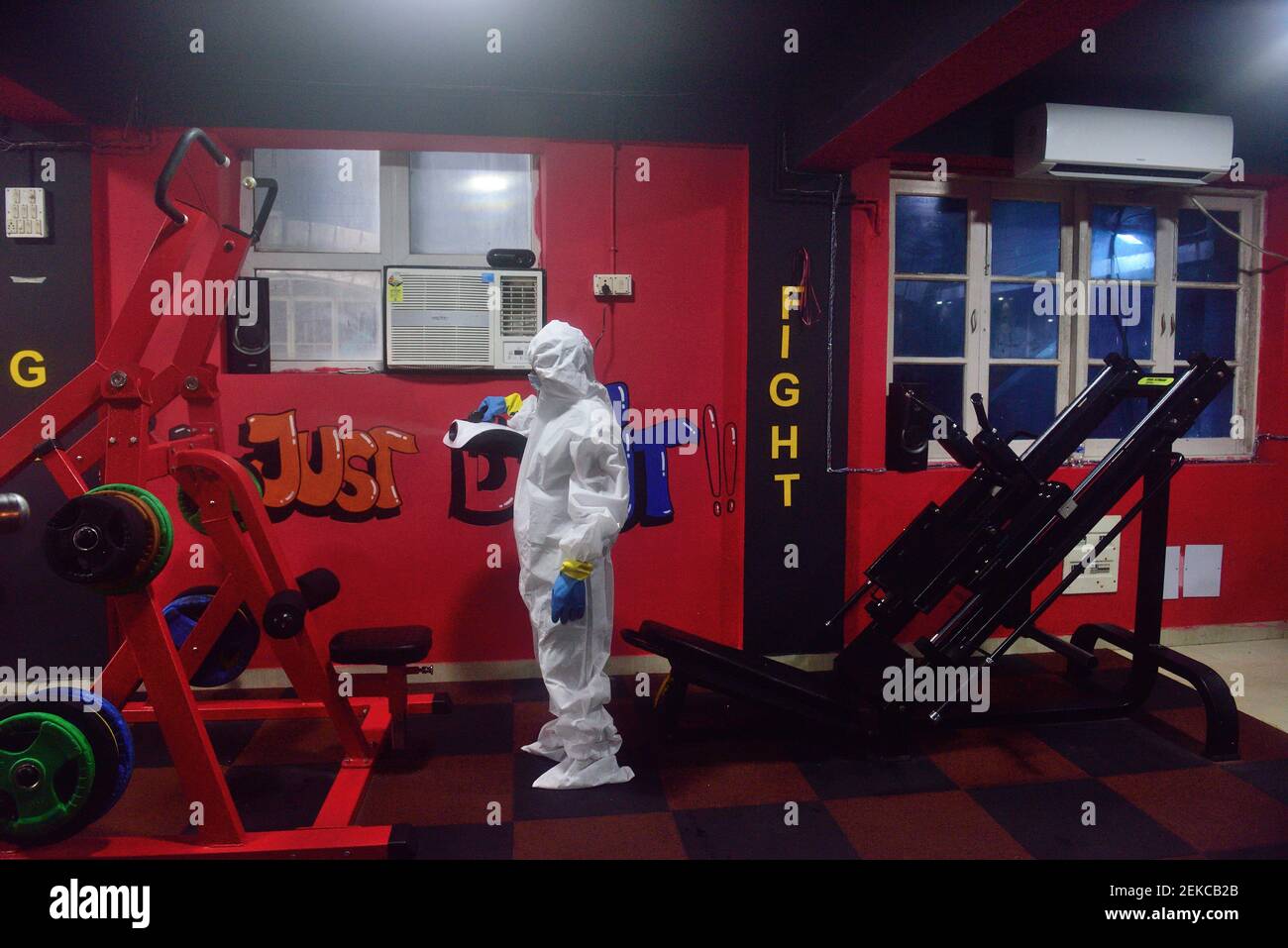 A worker wearing a personal protective equipment suit (PPE) sanitizes ...