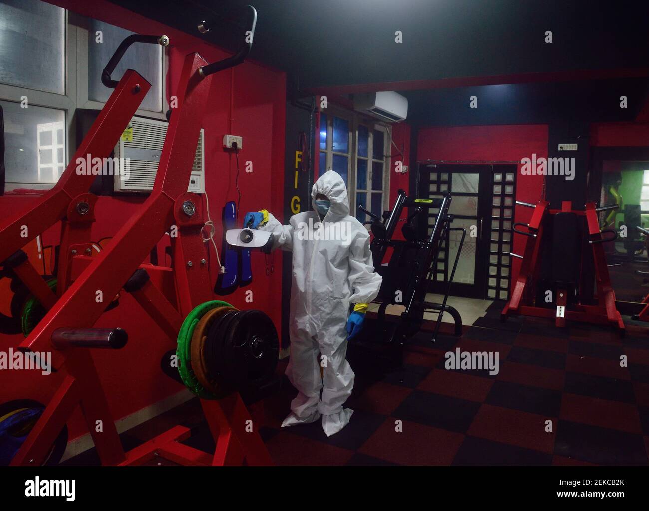 A worker wearing a personal protective equipment suit (PPE) sanitizes ...